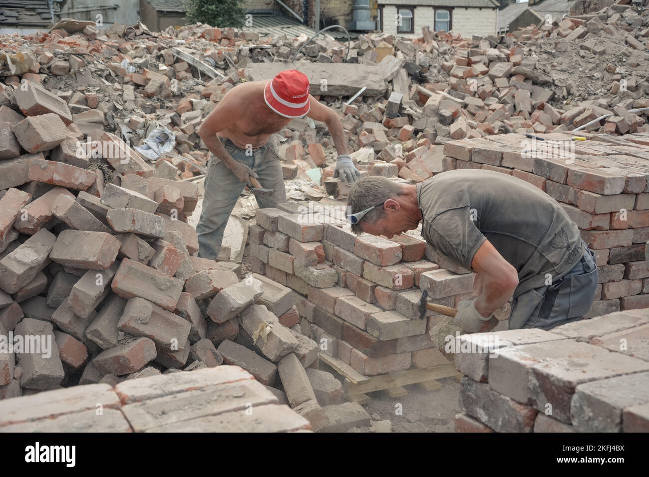 Pile of old reclaimed bricks on a pallet. Derelict terraced houses in ...