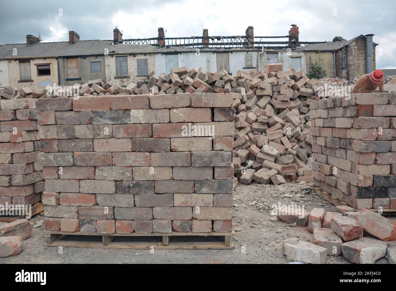 Pile of old reclaimed bricks on a pallet. Derelict terraced houses in ...
