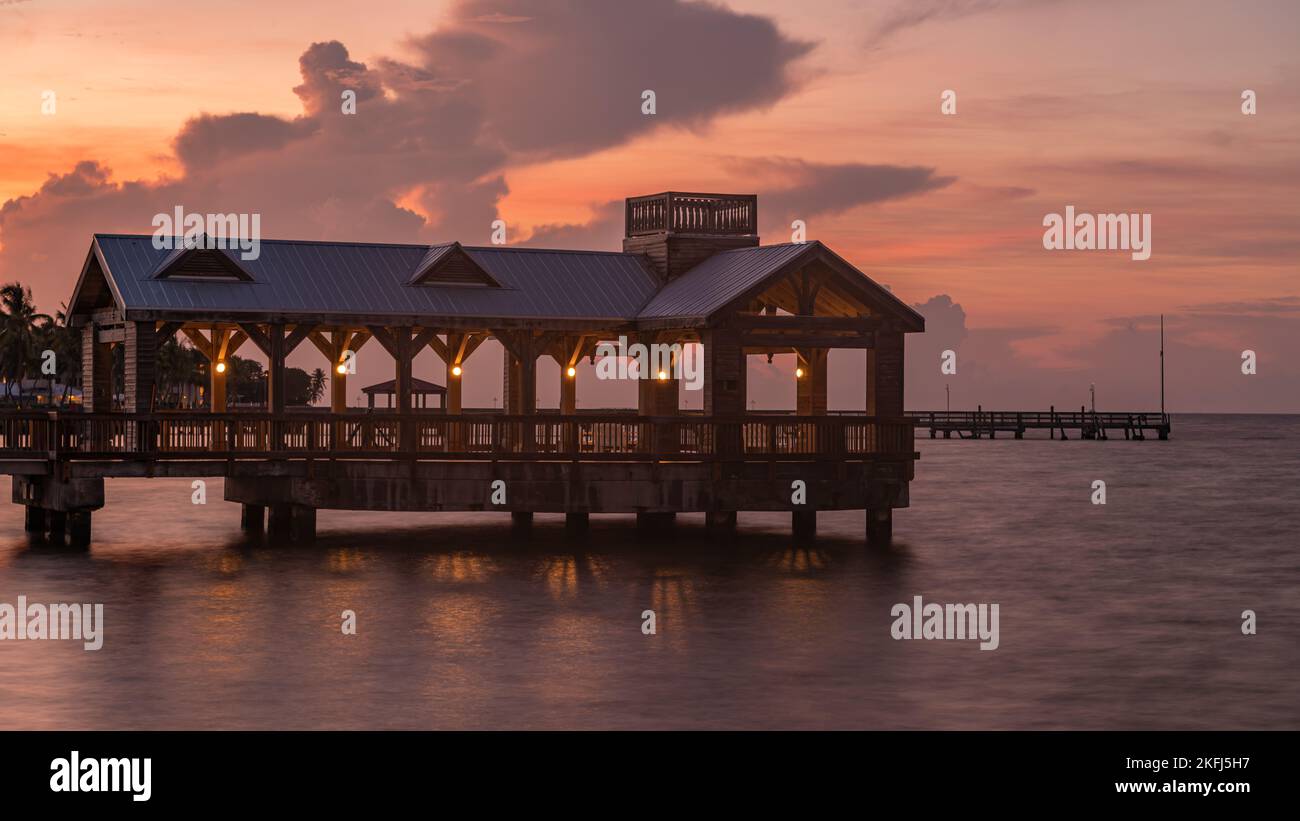 A breathtaking sunset sky over the wooden dock and a bar above the ...