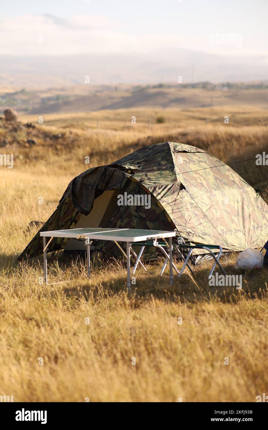 A combat tent, with military design, in the grassy field in autumn ...