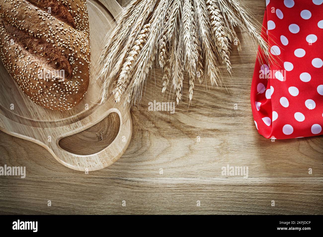 Bread carving board wheat ears red tablecloth on wooden background ...
