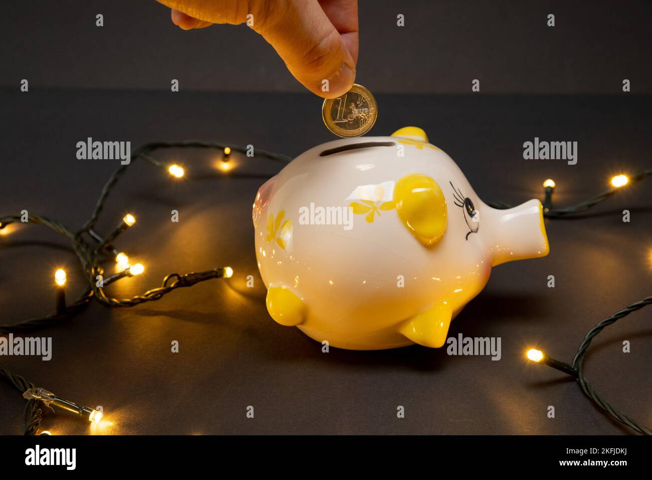 Putting one euro coin in a piggy bank, on a dark background with led ...
