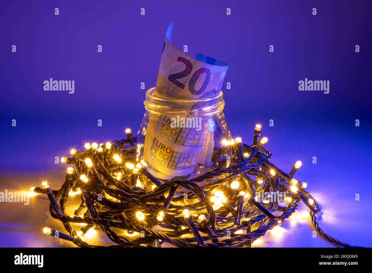 Glass jar with twenty euro banknote on a purple background, centered on ...