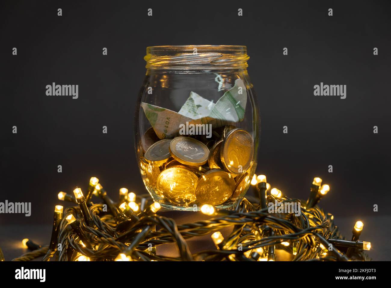 Glass jar with euro coins and paper boat centered on a dark background ...