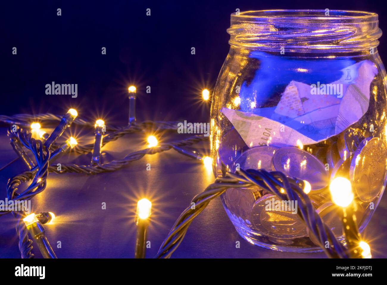 Glass jar with euro coins and paper boat on a dark background with led ...