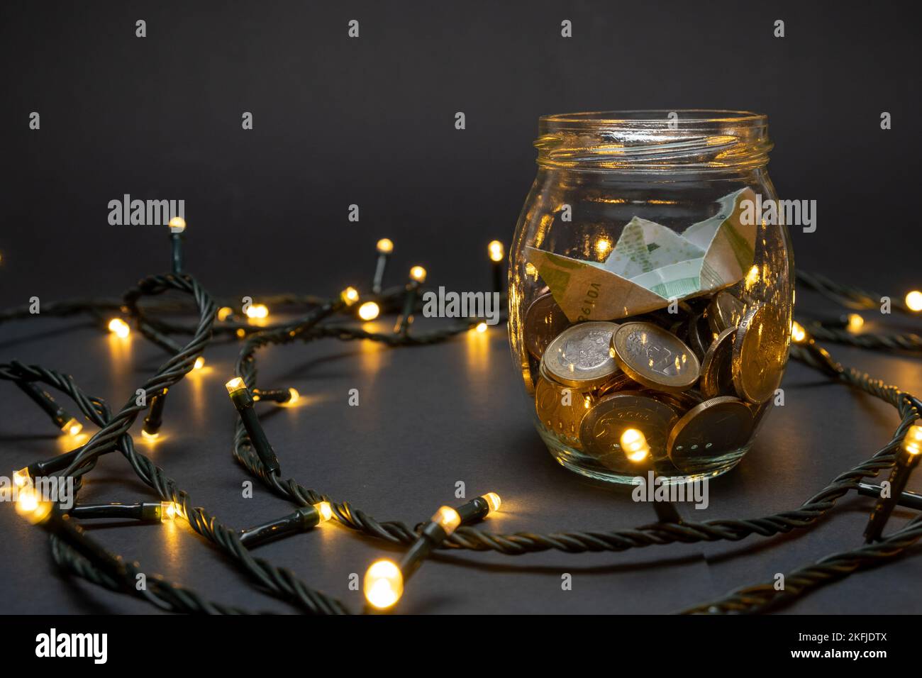 Glass jar with euro coins and paper boat on a dark background with ...