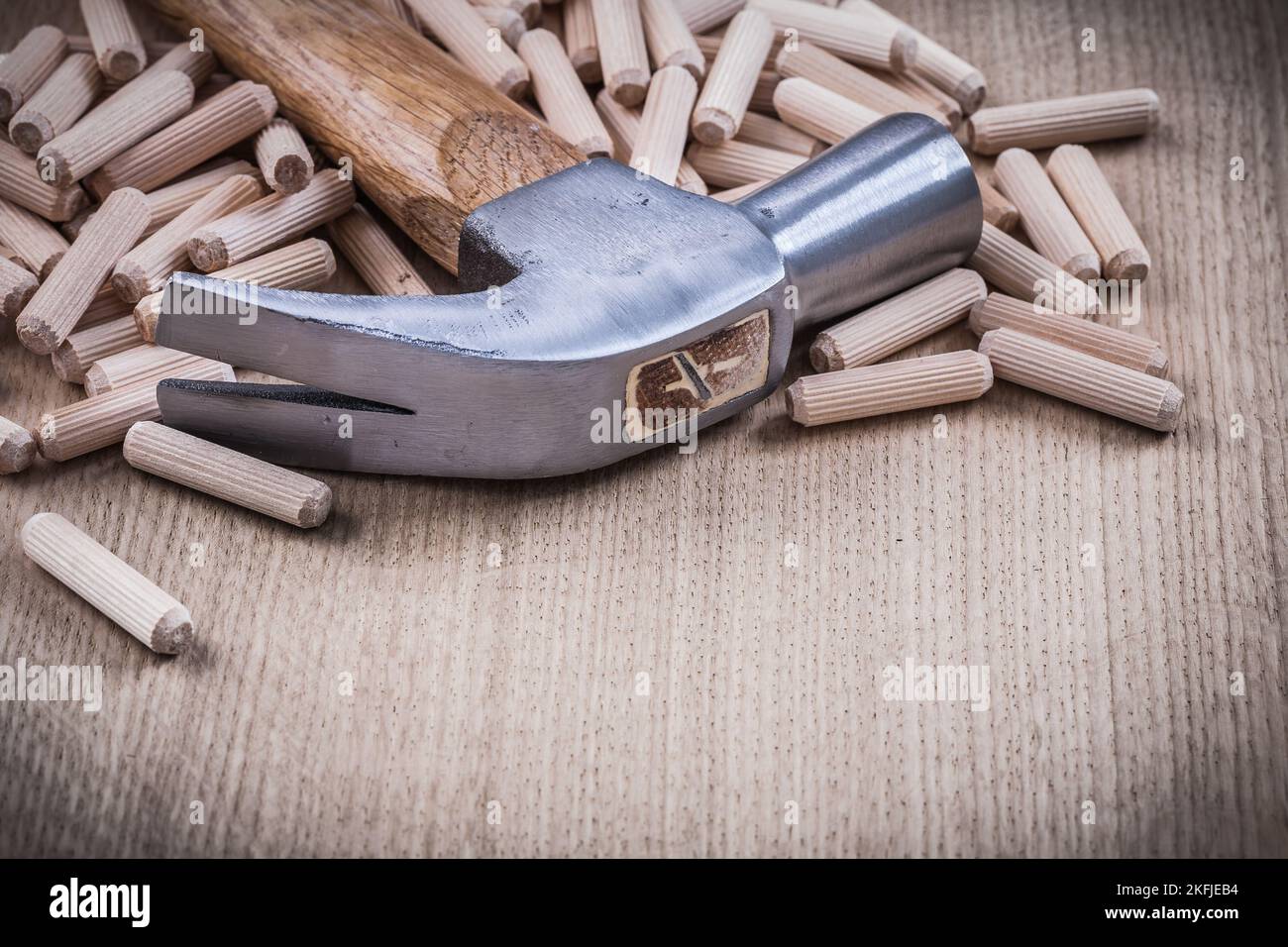 Dowel pins and metal hammer on wooden background construction concept ...