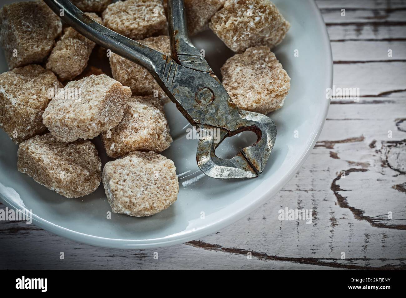 Heap of vintage brown sugar pliers saucer on wooden board Stock Photo ...