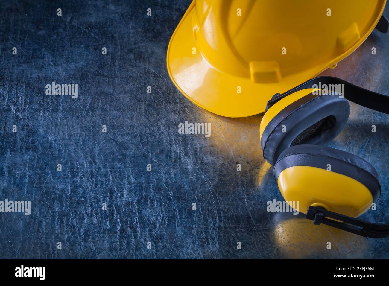 Noise insulation ear muffs and hard hat on scratched metallic ...