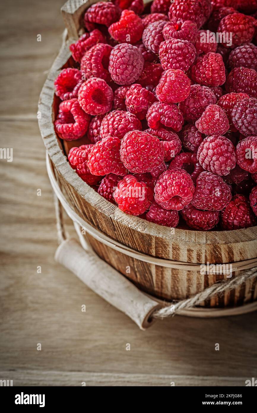 Ripe raspberries in bucket on wooden board Stock Photo - Alamy