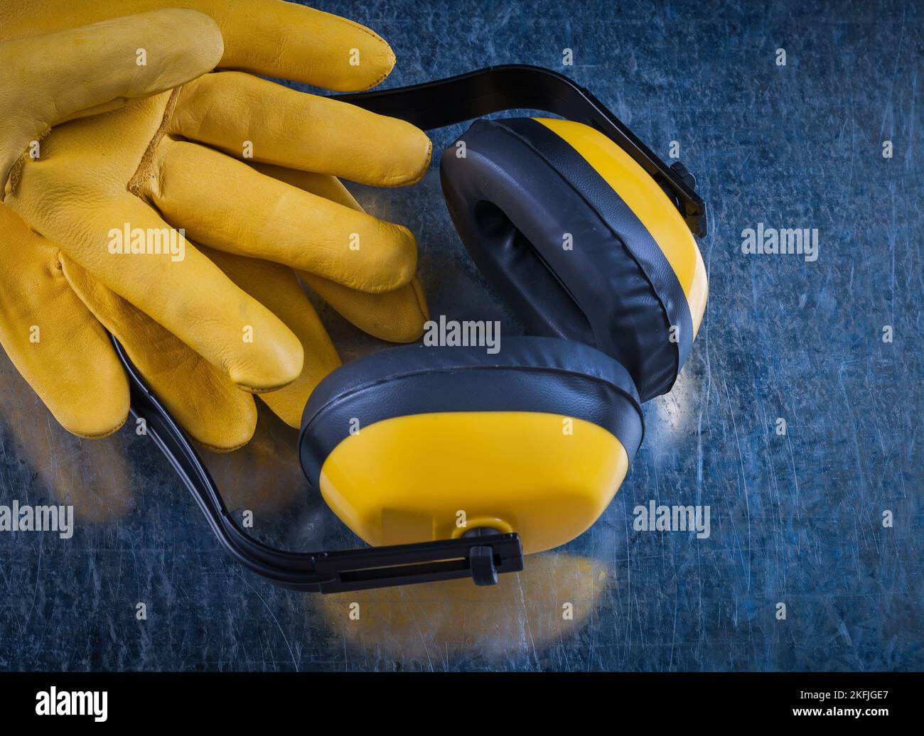 Safety yellow ear muffs and pair of leather construction gloves on ...