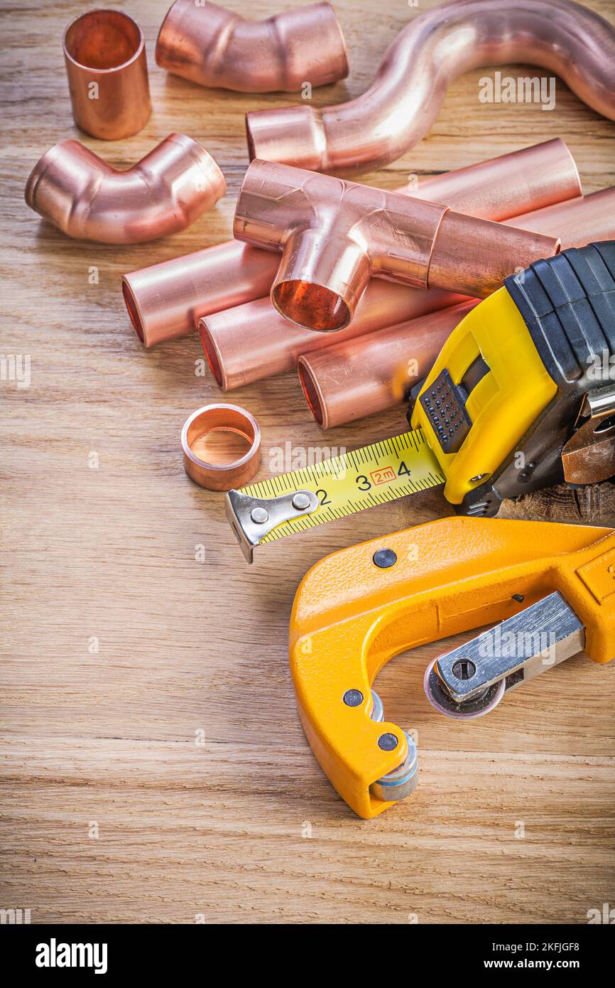 Set of copper water pipe cutter fixtures tape line on wooden board ...