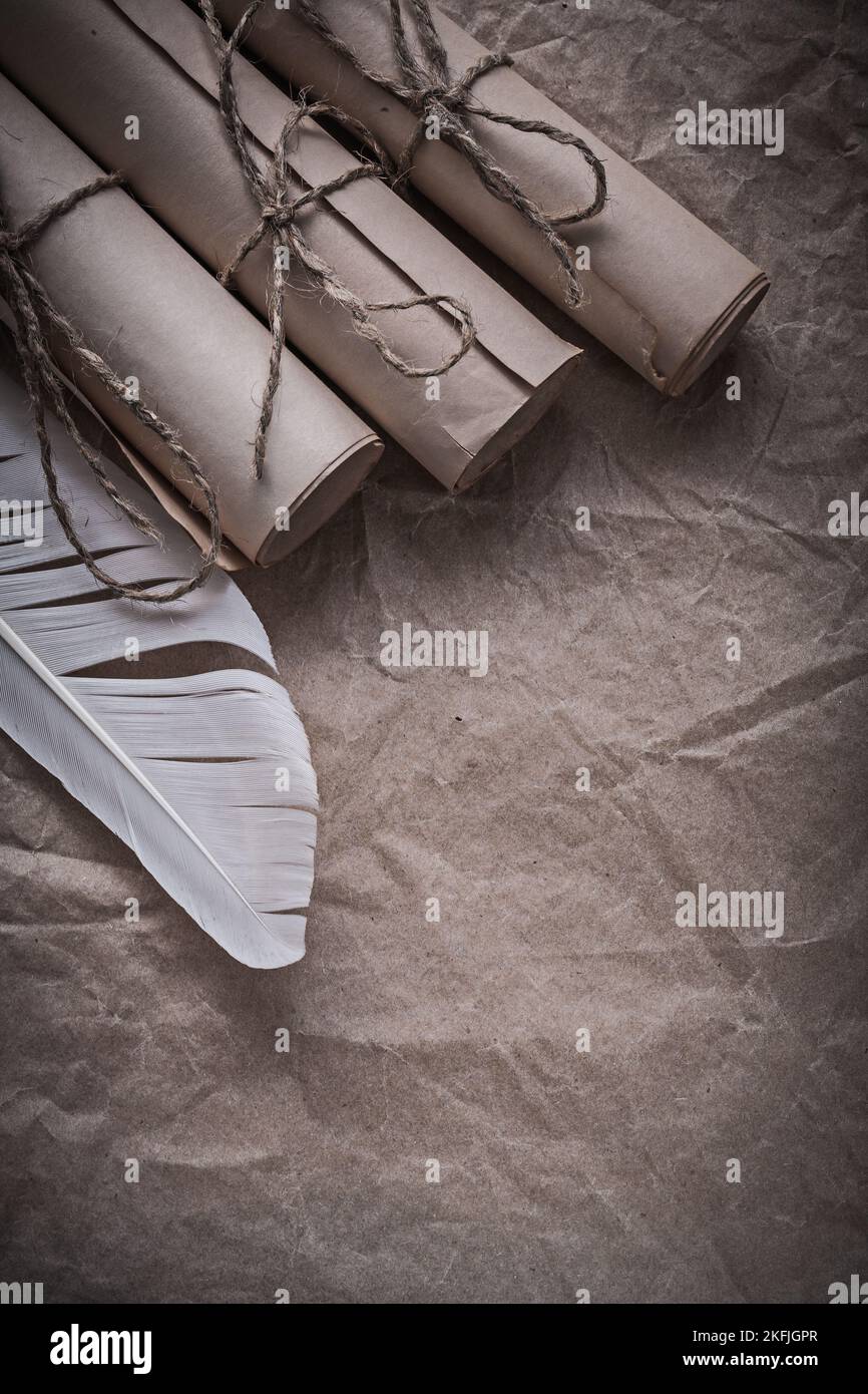 Stack of vintage paper scrolls feather on crumpled wrapping sheet Stock ...