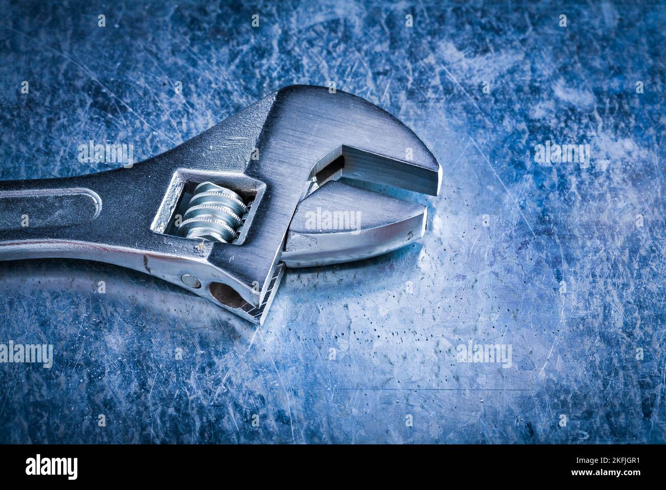 Stainless adjustable spanner on scratched metallic background top view ...