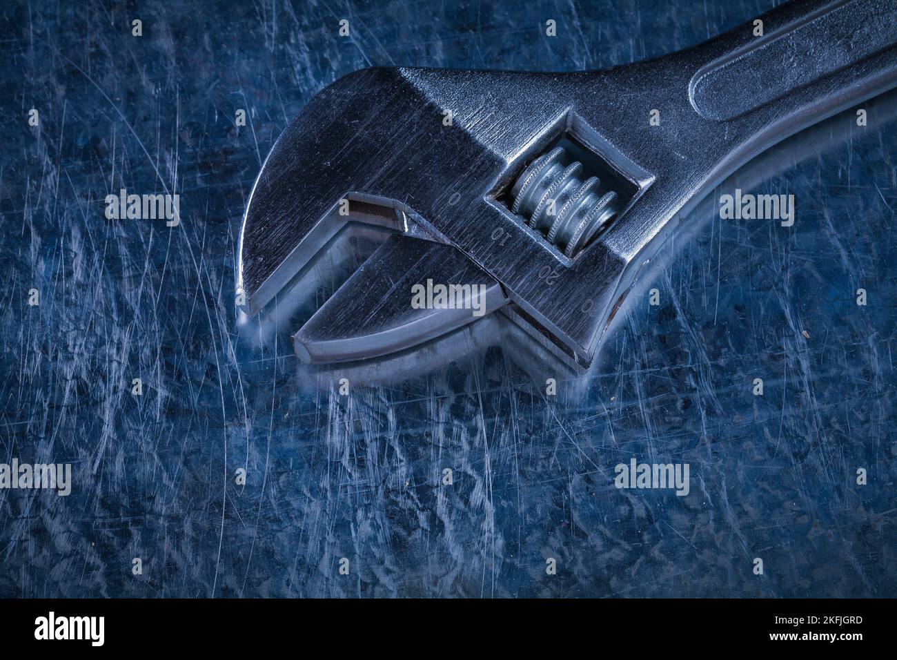 Stainless adjustable spanner on scratched metallic background ...