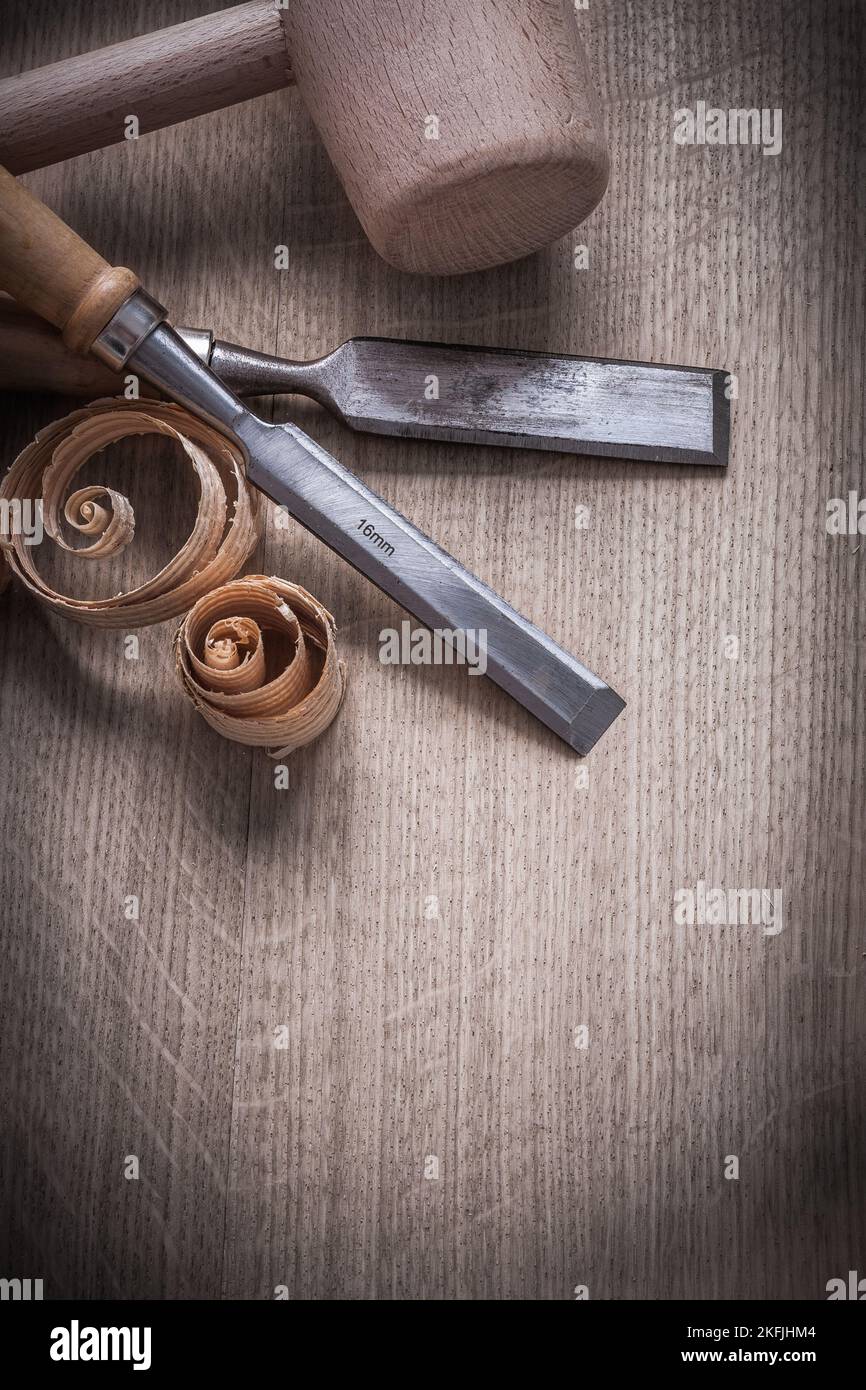 Wooden hammer curled up planning chips flat chisels on wood board ...