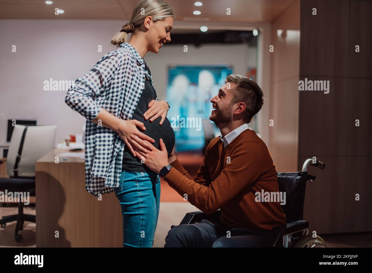A businessman with a disability holding his pregnant wife's stomach in ...