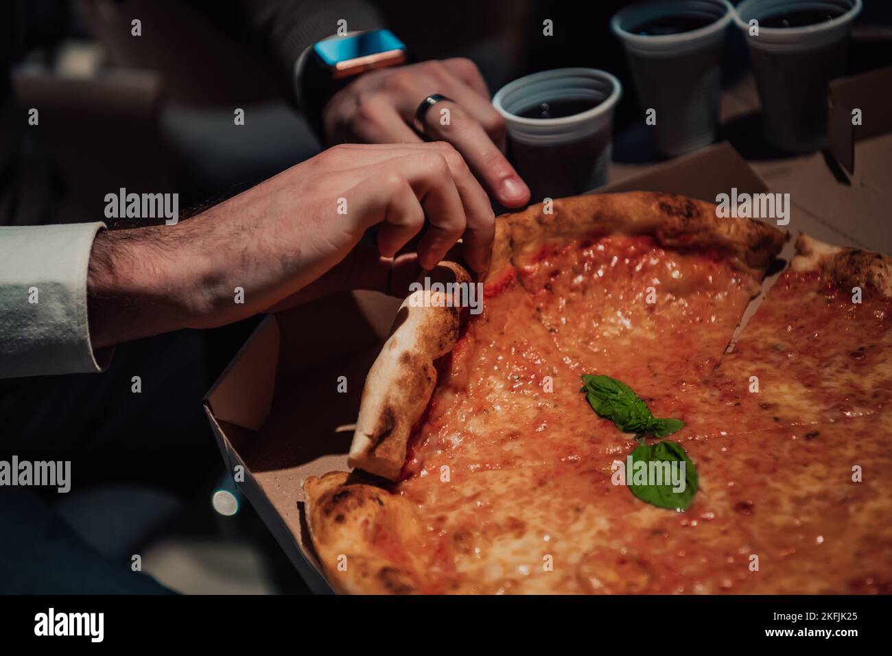 Close up photo of busy people eating pizza in the office during a break ...