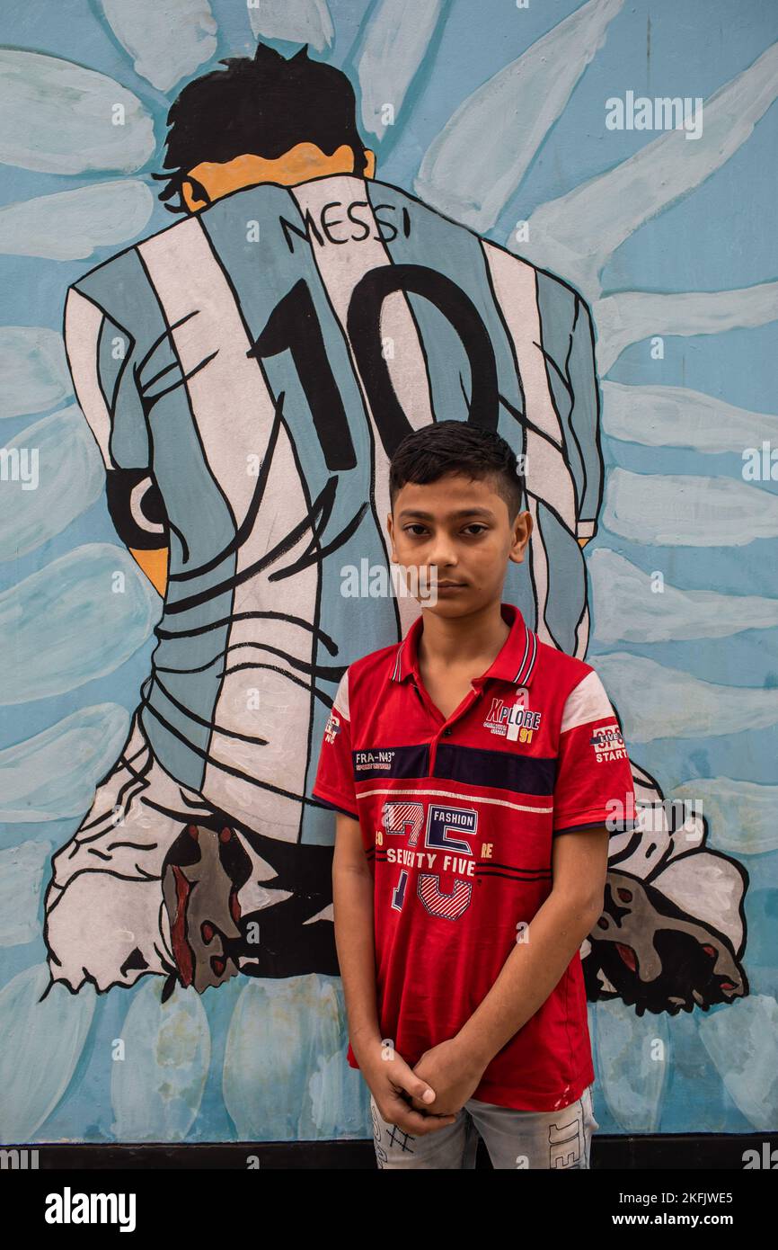 A boy poses in front of a graffiti of famous Argentine football star ...