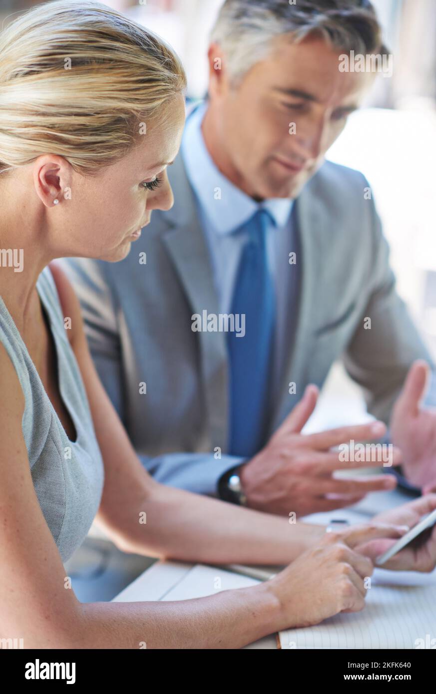Making informed business decisions. two mature businesspeople talking together of a digital ...