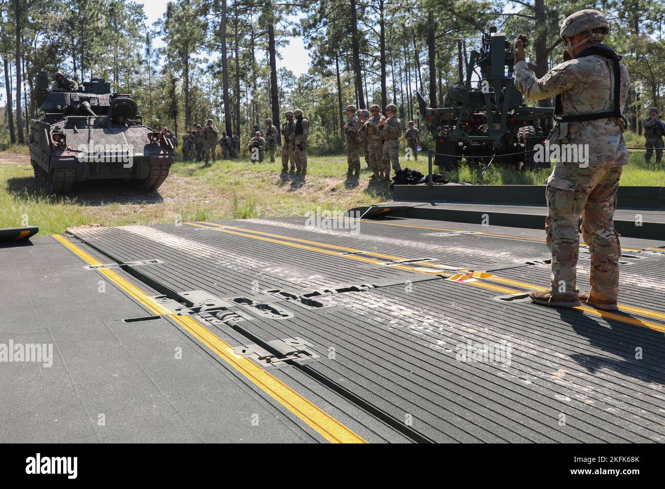 An M2A4 Bradley Fighting Vehicle is guided onto a bridge during a Wet ...