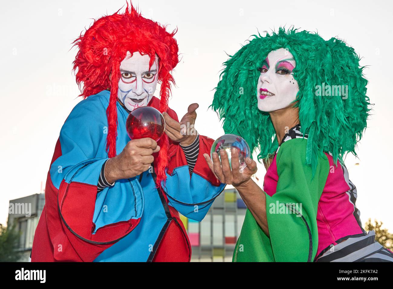 Male and female clowns in colorful costumes and wigs, looking at the ...