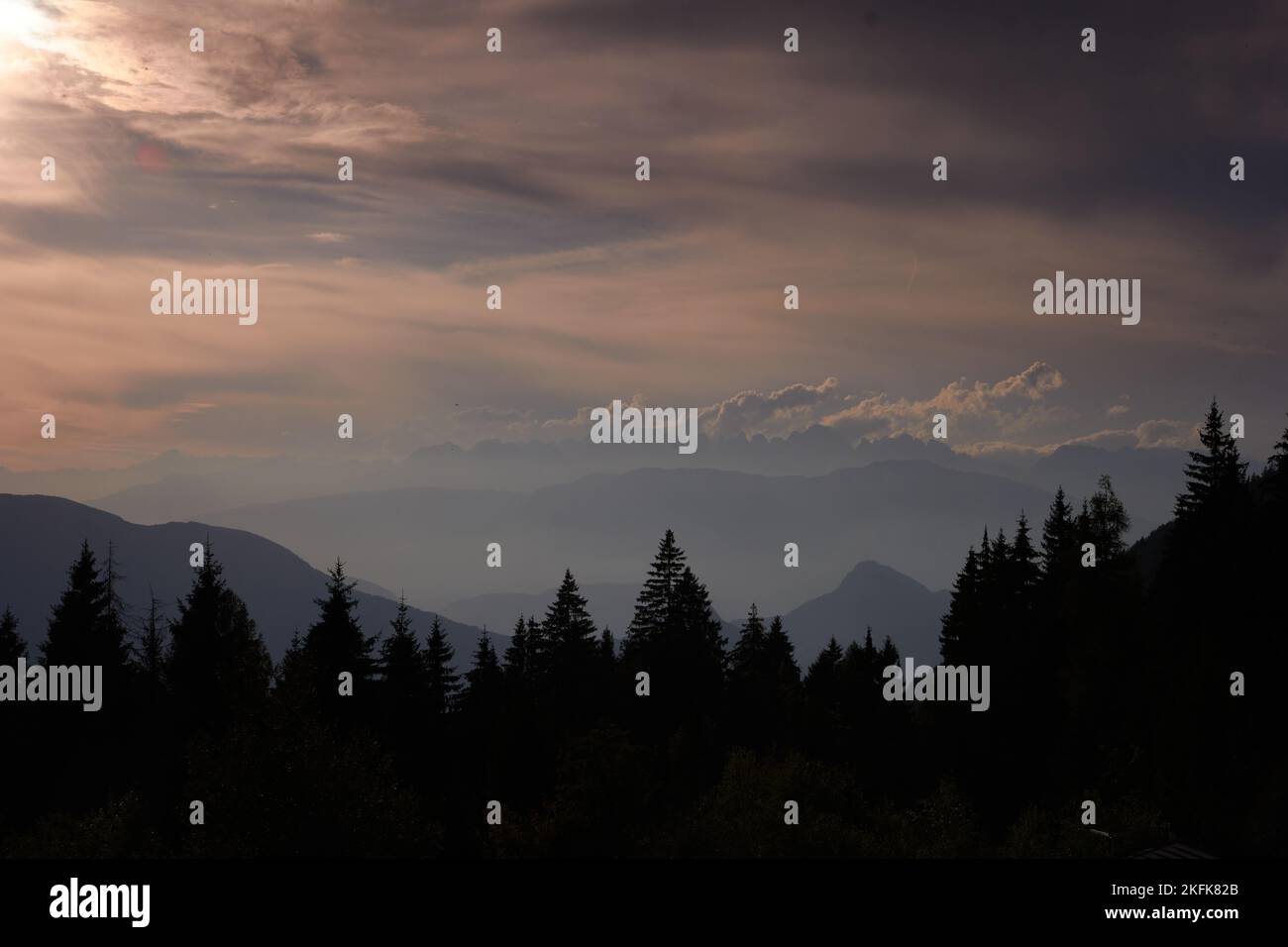 A beautiful view of a sunset sky with clouds over large trees in a ...