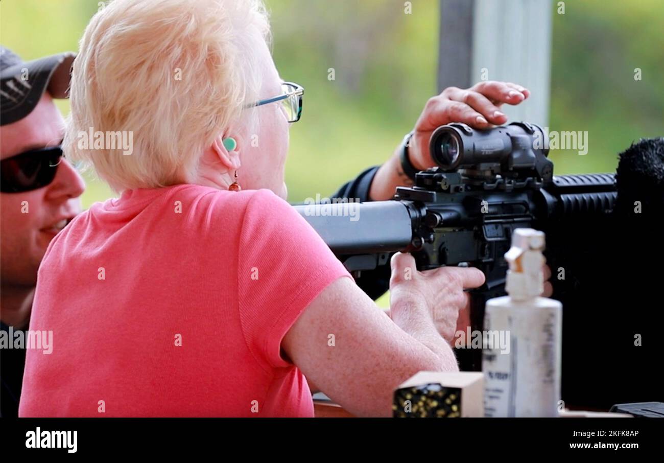 A Green Beret explains an M4 Carbine aiming sight during a family range ...