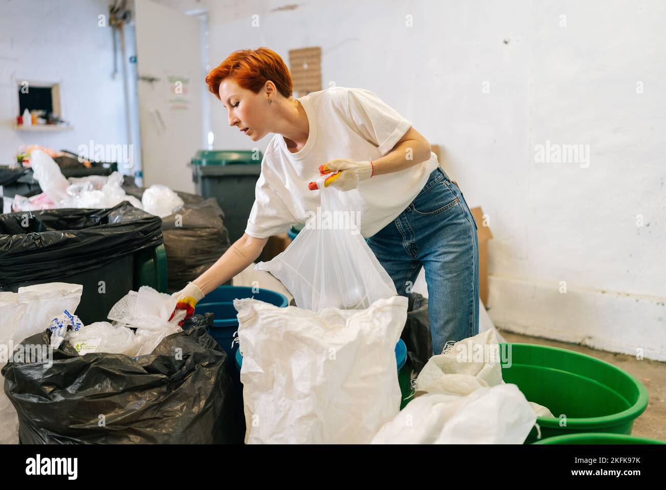 Side view of redhead female worker wearing latex gloves sorting diverse ...