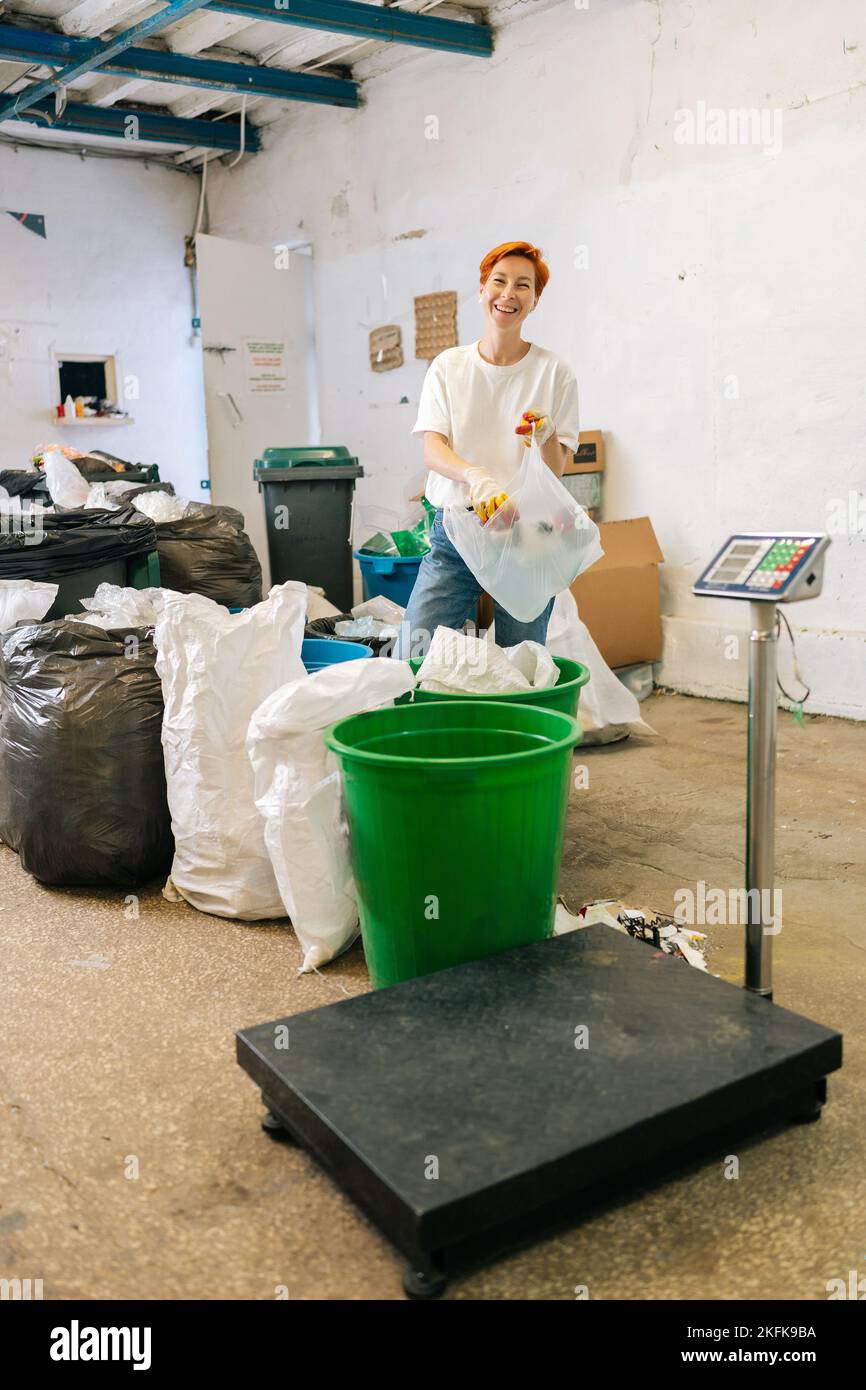 Vertical portrait of smiling female worker in latex gloves looking at ...