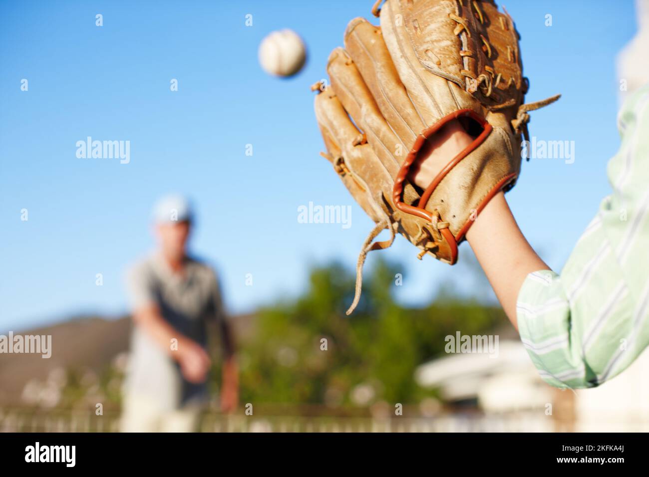 Thats one in the mitt. a father and son throwing the baseball outdoors ...