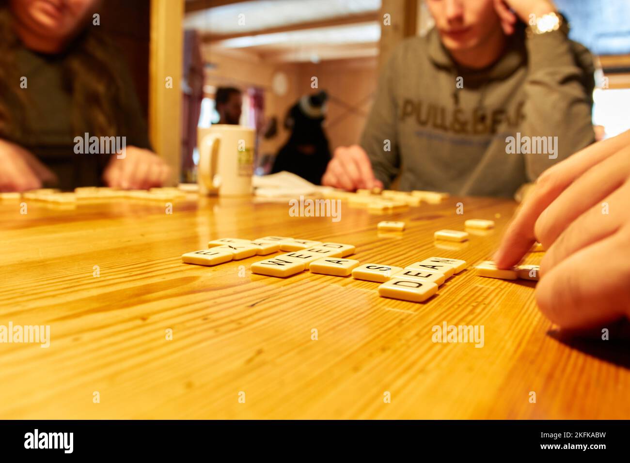 Friends playing Scrabble board game while sitting Stock Photo - Alamy