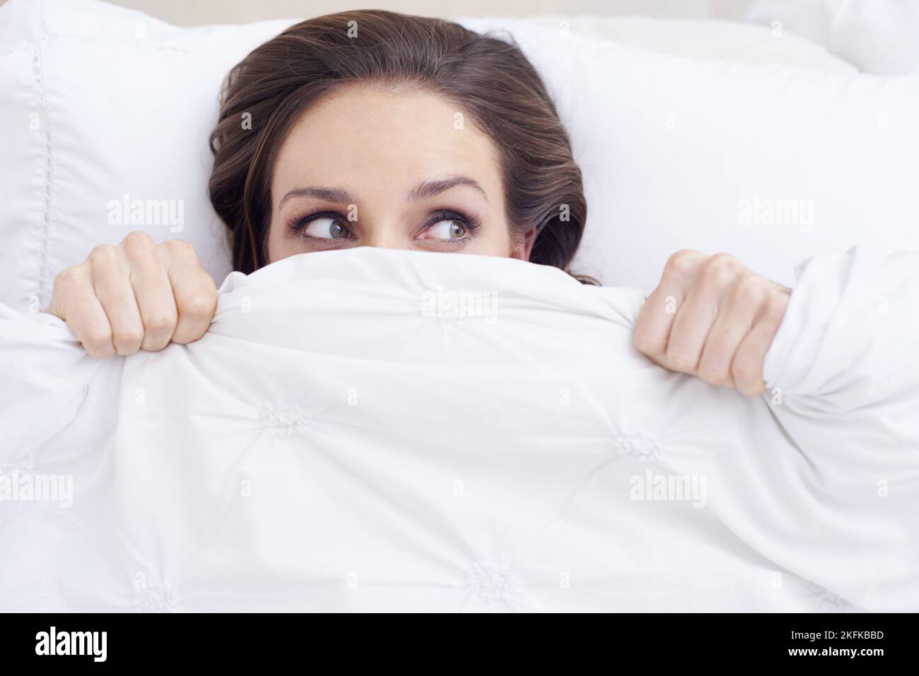 Something went bump in the night...A young woman peeking out from under ...