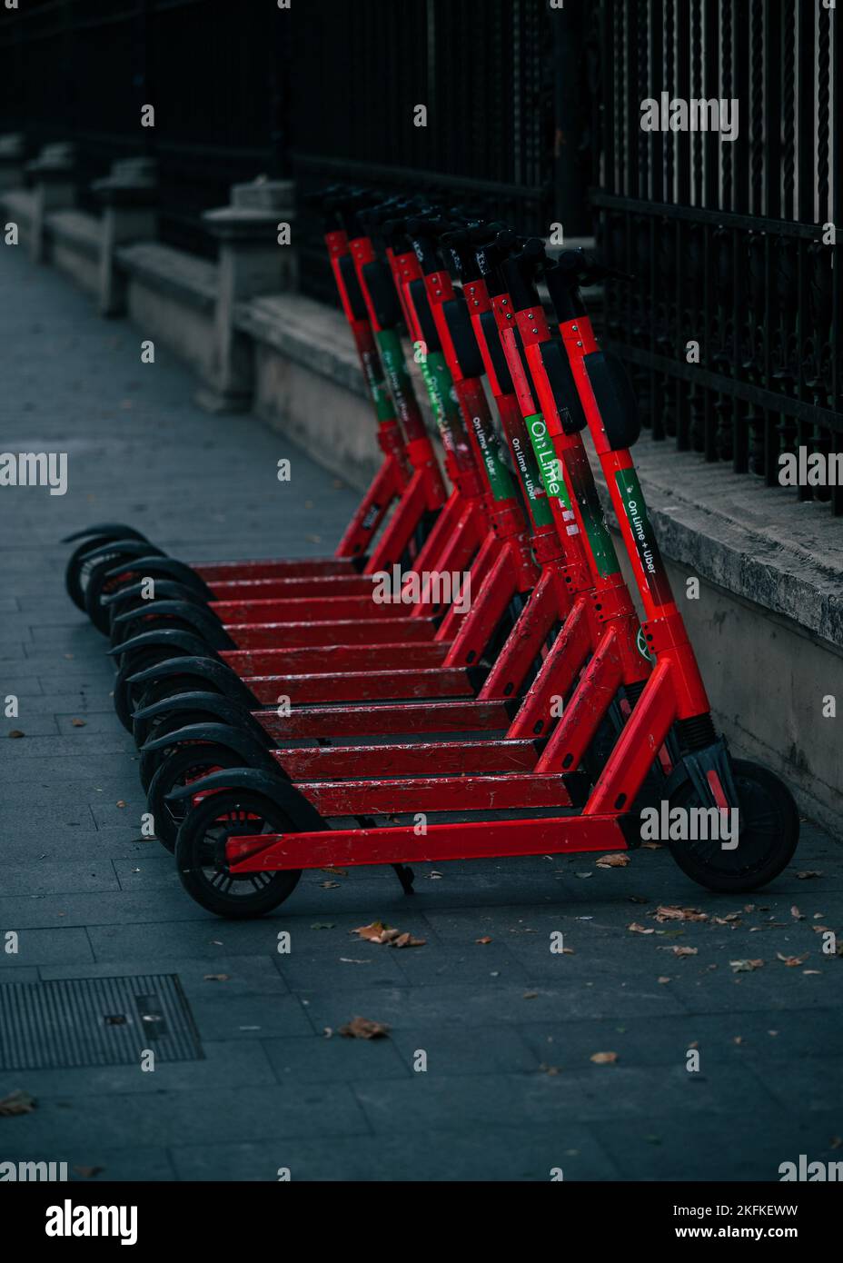 A vertical shot of electric scooters stack parked on the street behind ...