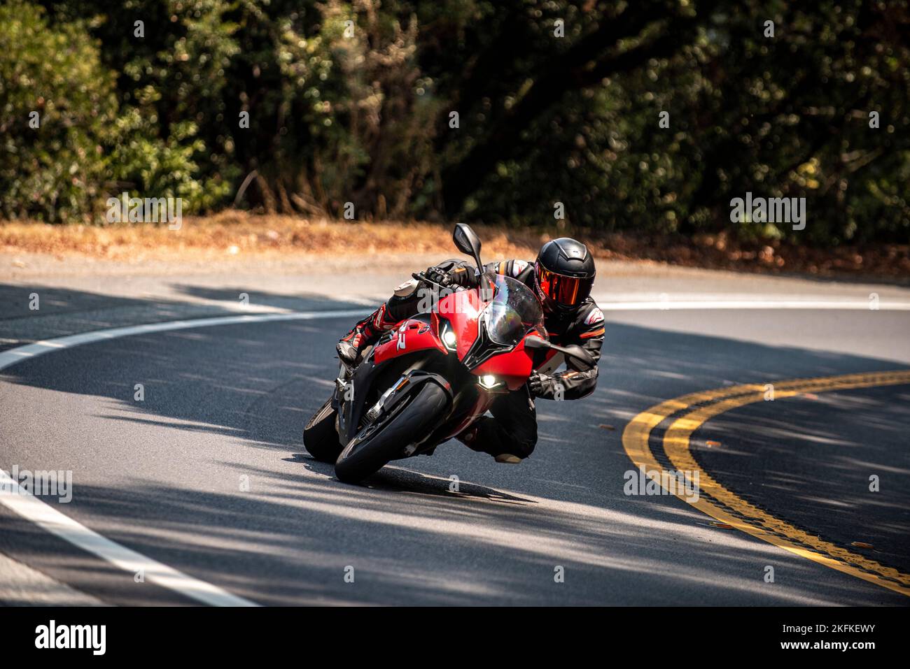 A motorcyclist on a red sports bike riding fast through a left-hand ...