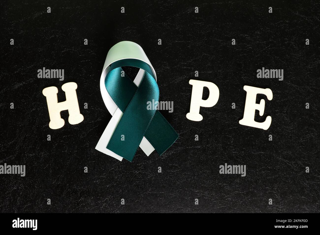 Top view of with word hope teal and white ribbon in dark black ...