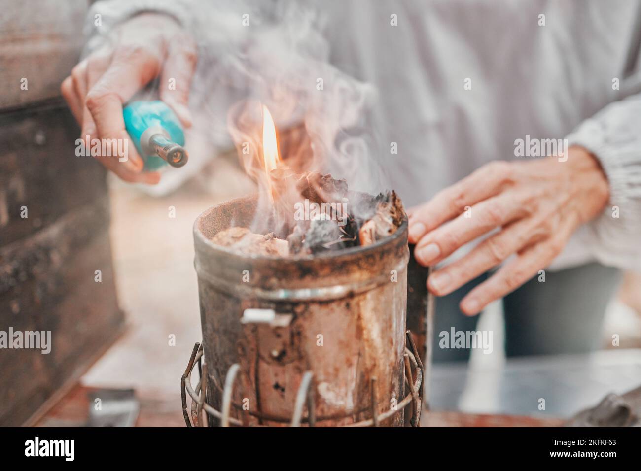 Fire, camping and hands of a senior person start a flame for heating ...
