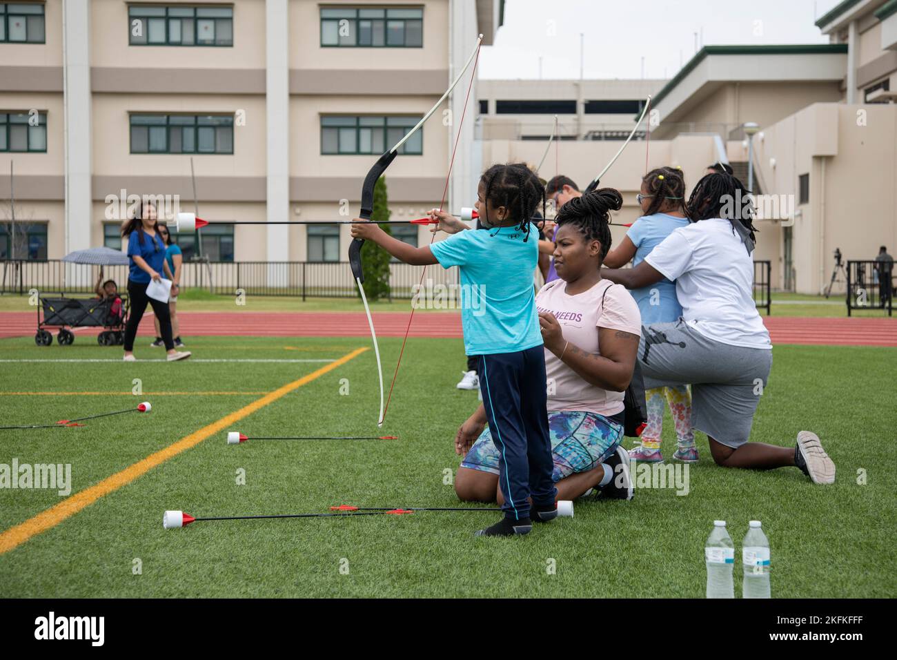 Families participate in a bow and arrow activity during the first-ever ...