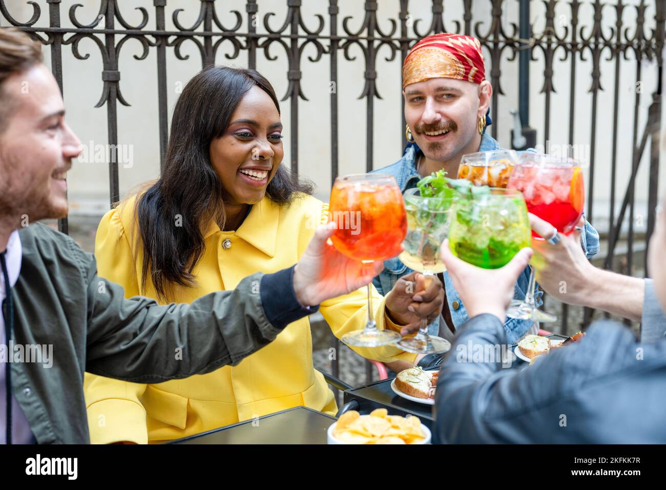 group of diverse people toasting drinks at cocktail bar, friends having ...