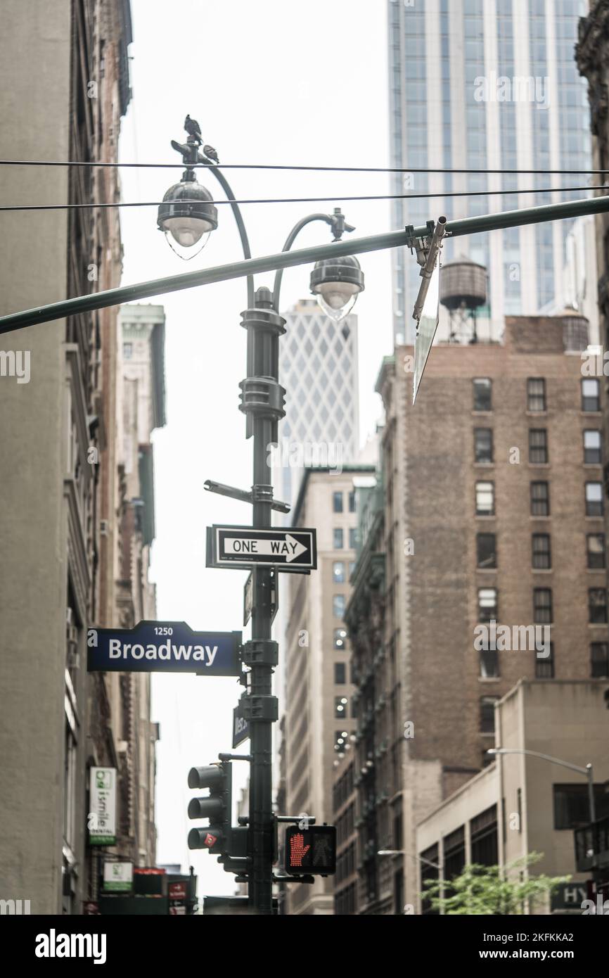 A closeup of Broadway street sign and one way sign with traffic light ...
