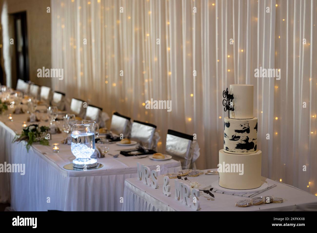 The wedding table setting in cream tones and a festive cake with black ...