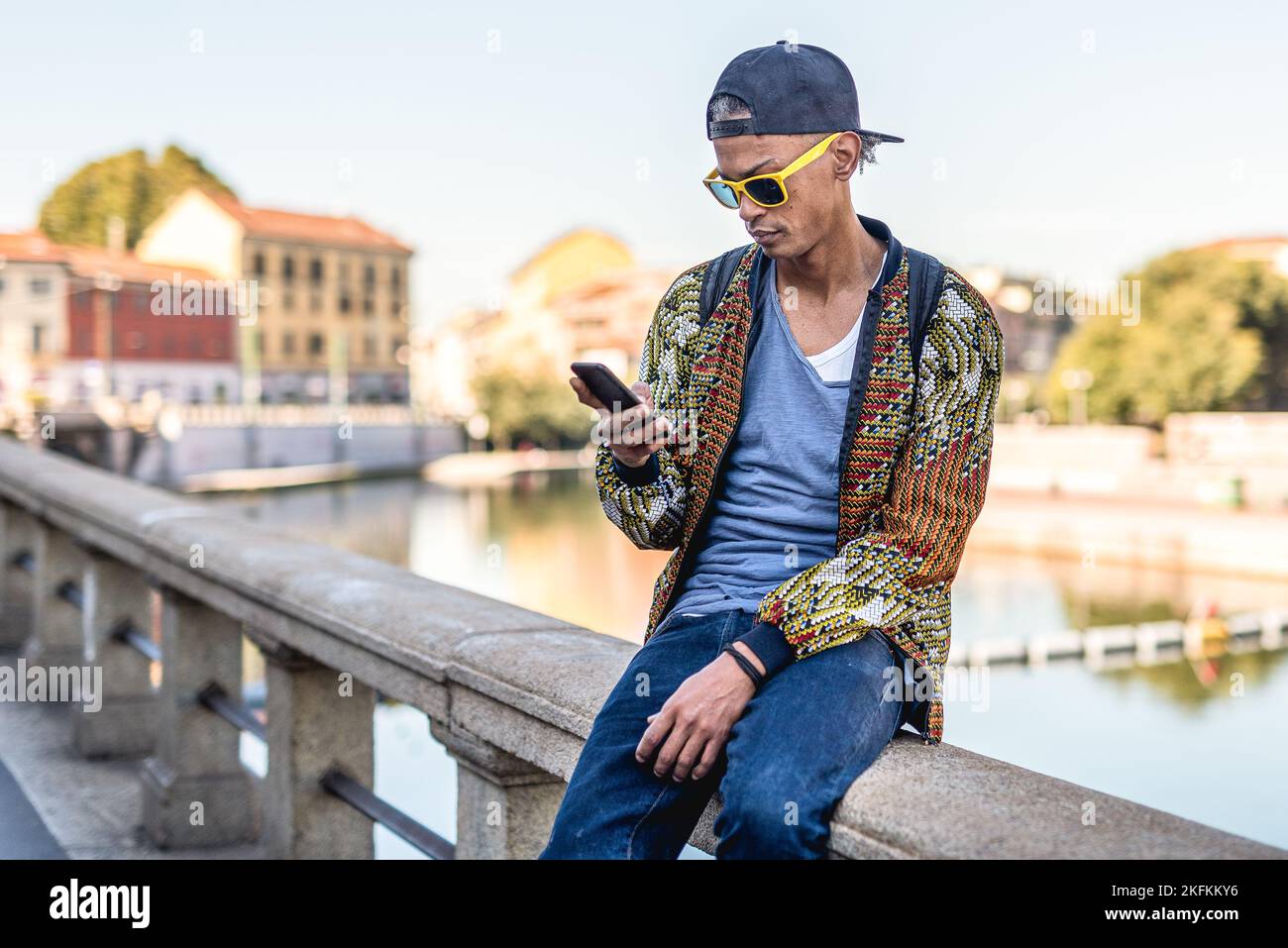 Young trendy man looking at his smartphone, social network addicted guy ...