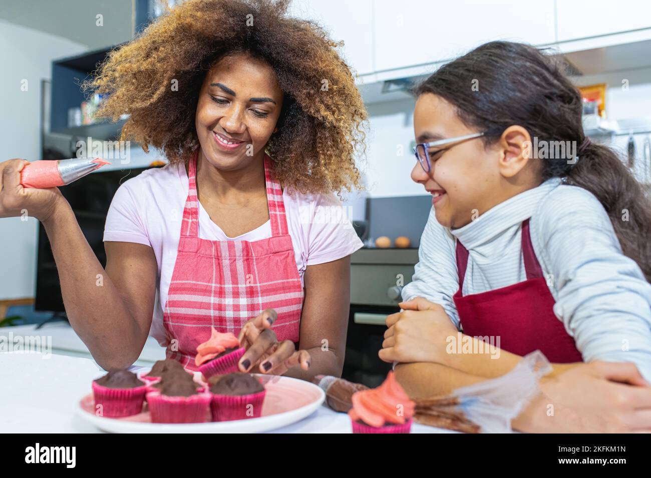 mother and daughter cooking pastries in the kitchen, latin adult woman ...