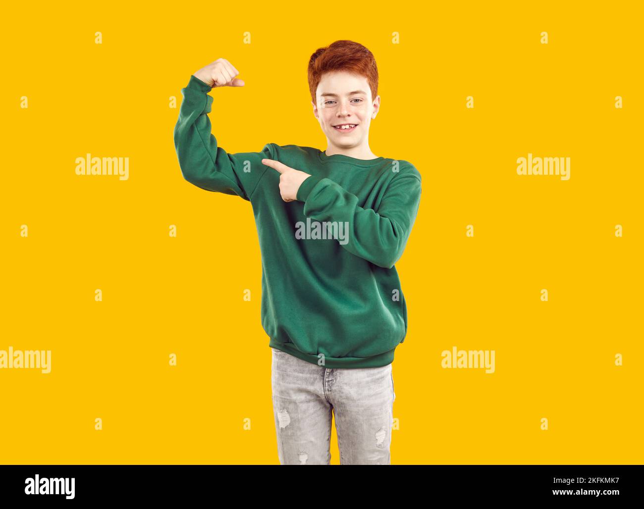 Red-haired, smiling, confident teenager, demonstrates bicep on one arm ...