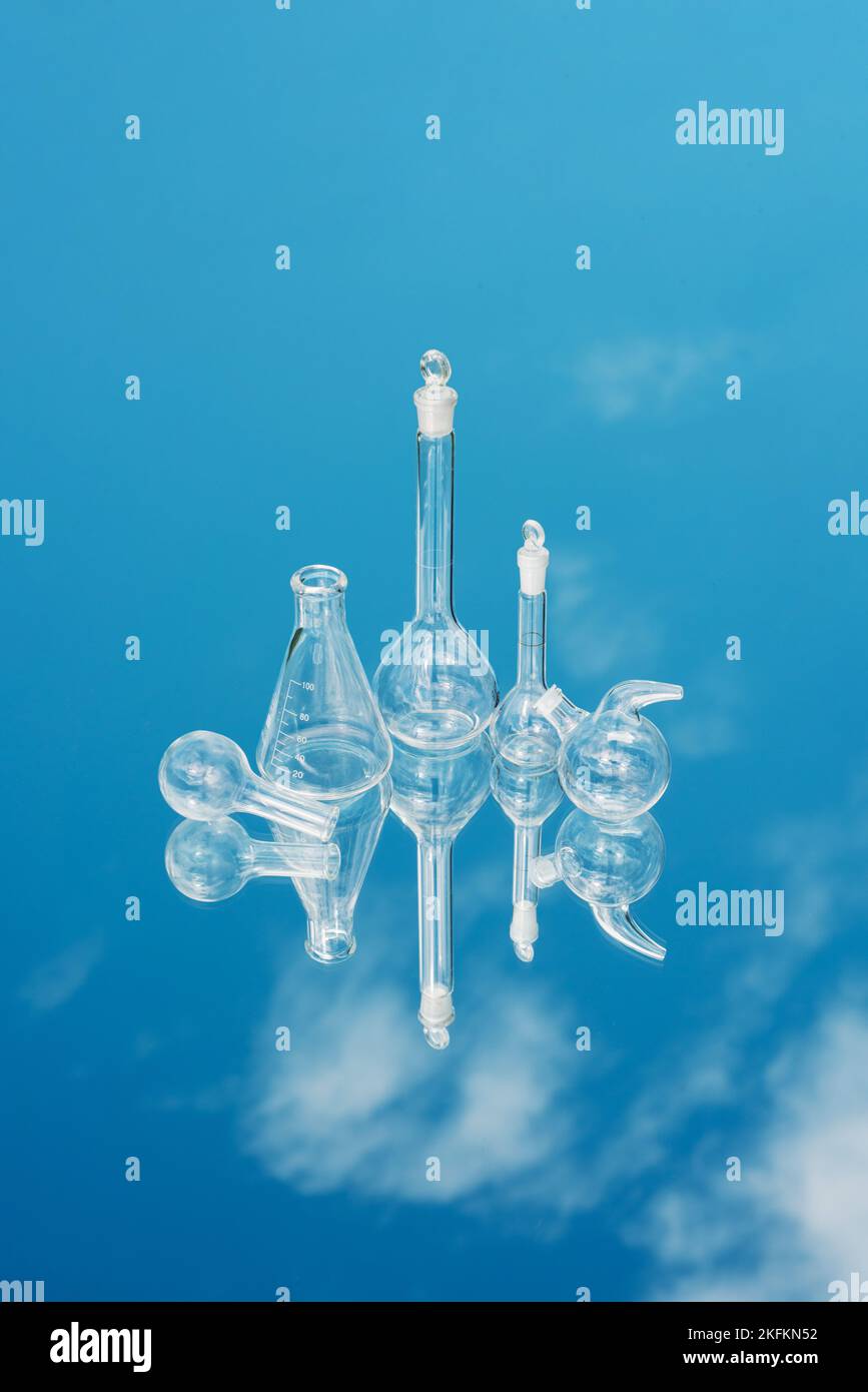 Various laboratory glassware on a mirror background with sky reflection ...
