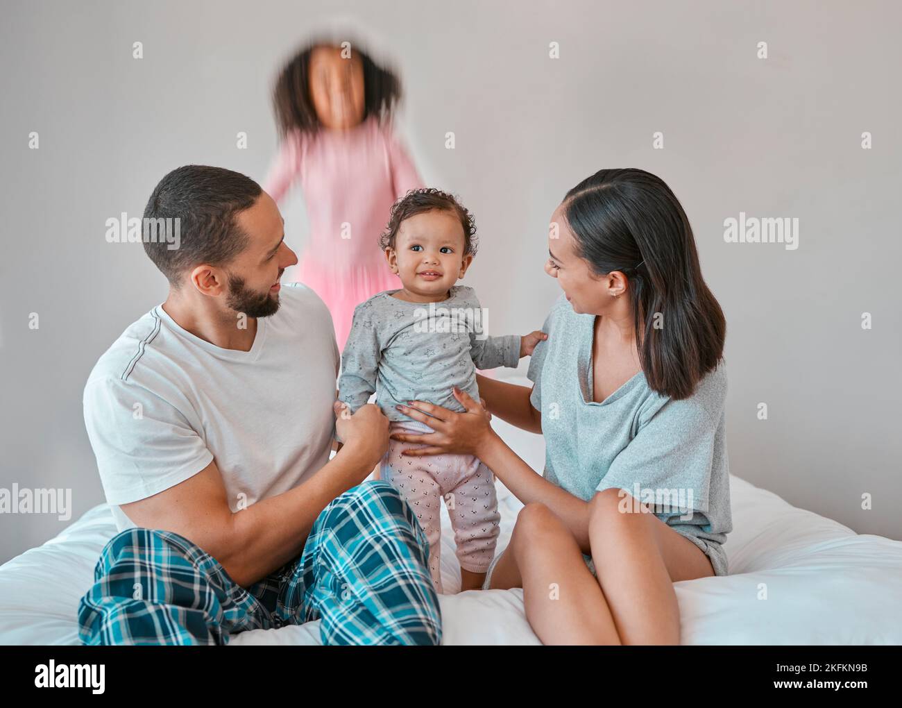 Family, baby and girl jump on bed in bedroom, having fun or playing ...
