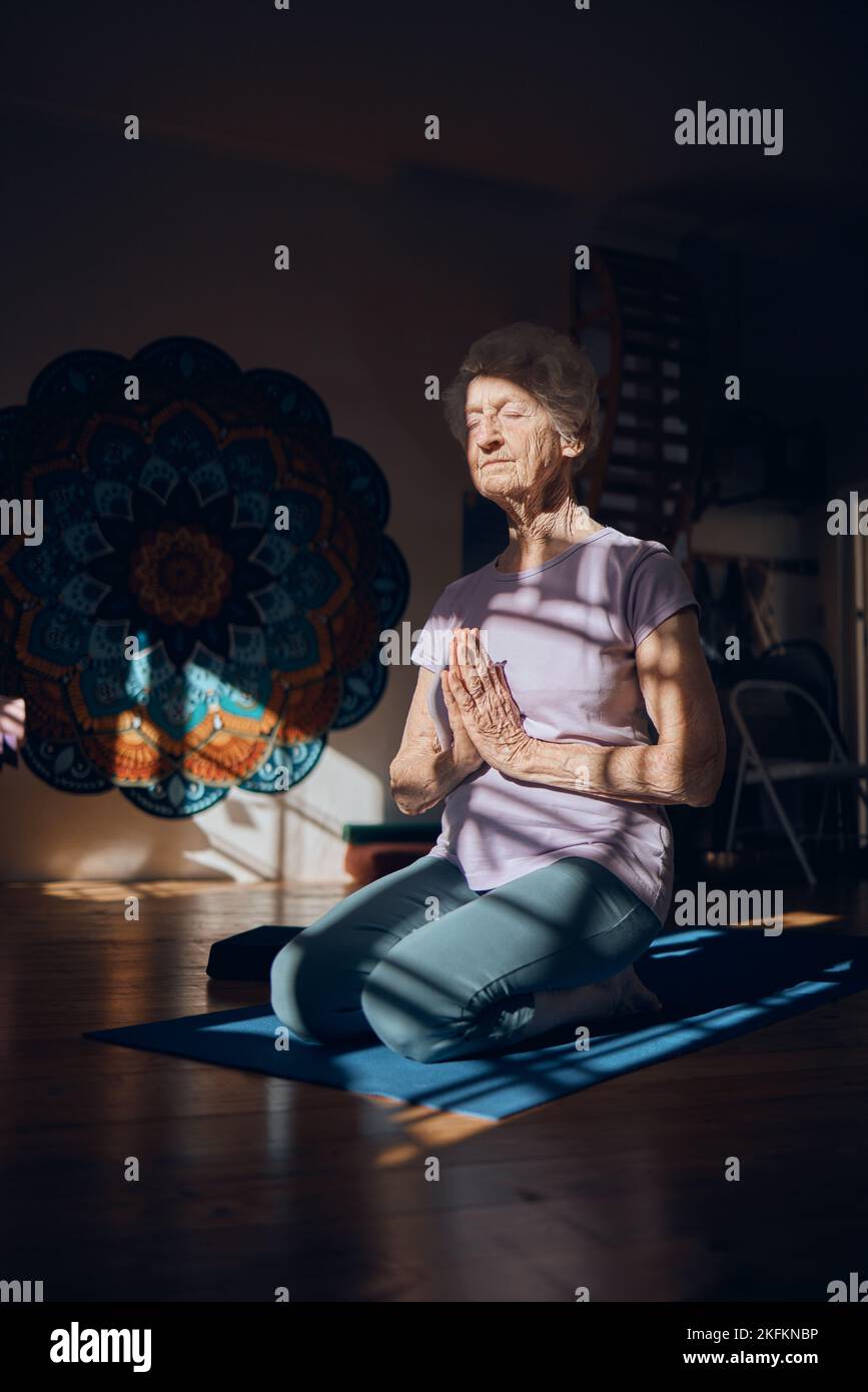 Meditation, zen and elderly woman doing yoga in dark room, shadow and ...