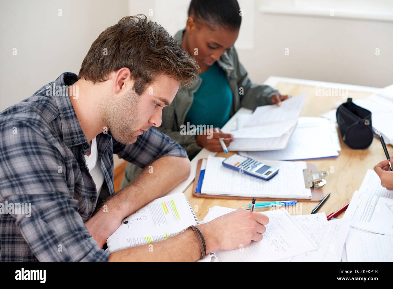Keeping each other focused. three university students studying Stock ...