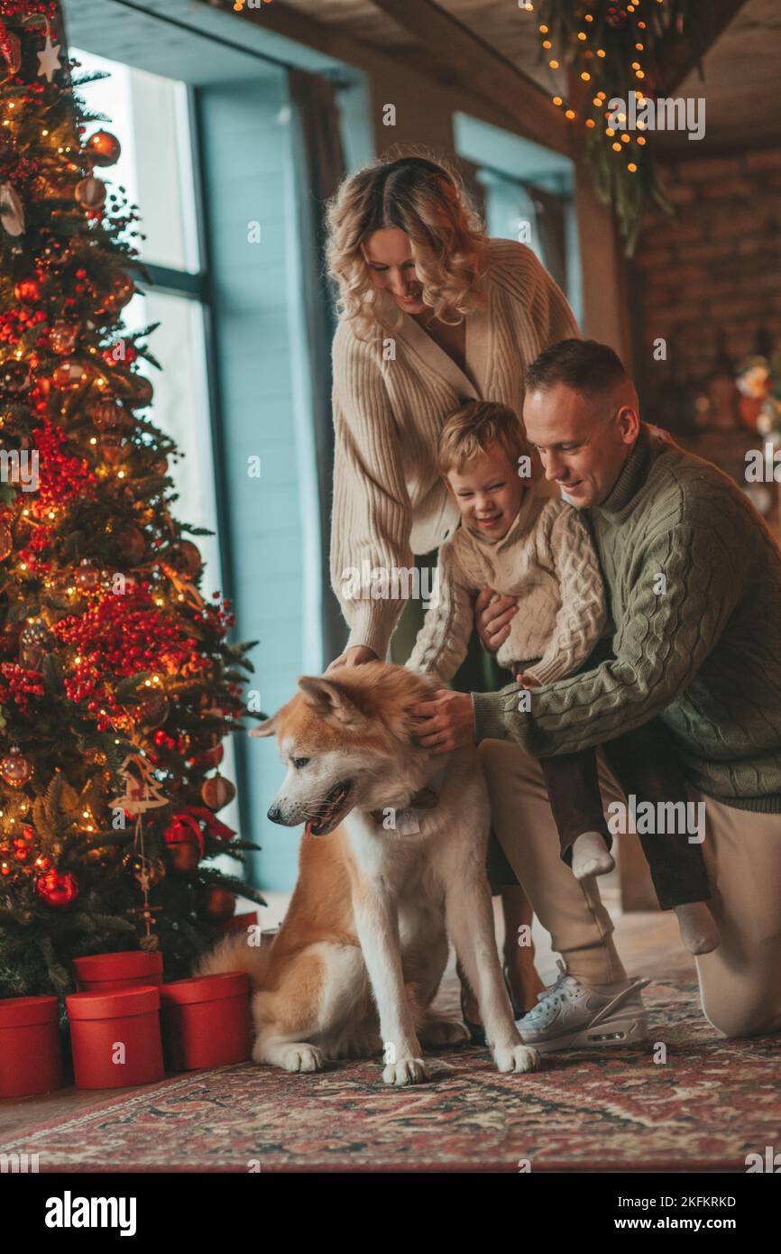 Portrait of happy family in knitted beige sweaters waiting Santa indoor ...