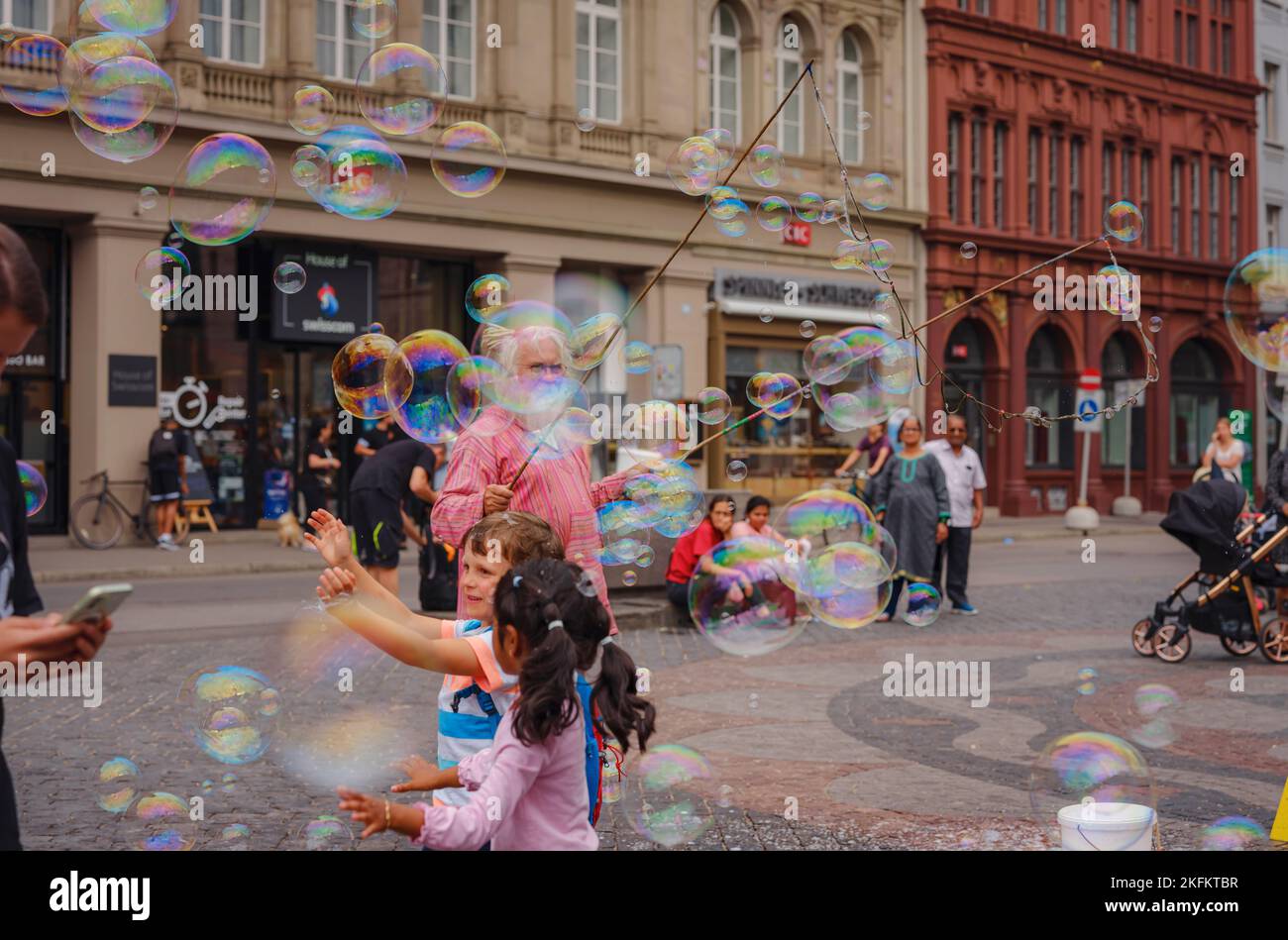 BASEL, SWITZERLAND, JULY 7, 2022: man blows bubbles and entertains kids ...